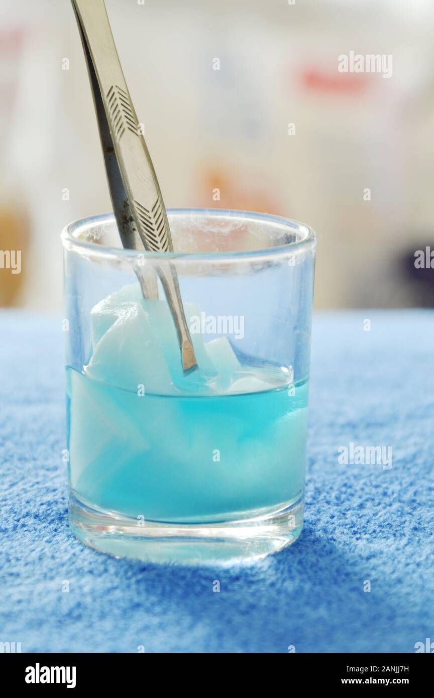 cotton wool with tweezers picking in blue alcohol on glass Stock Photo ...