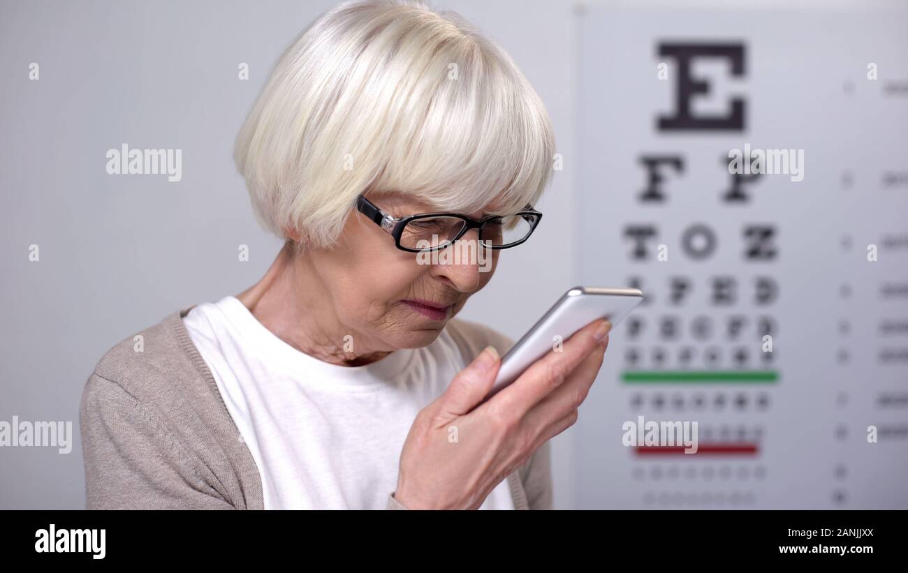 Elderly female trying to read on smartphone, small font, poor vision ...