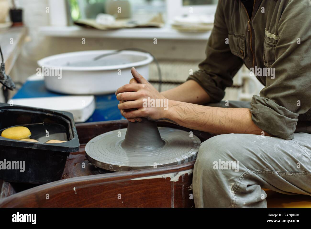 The girl sits at the Potter's wheel and creates a pot of ceramics. A ...