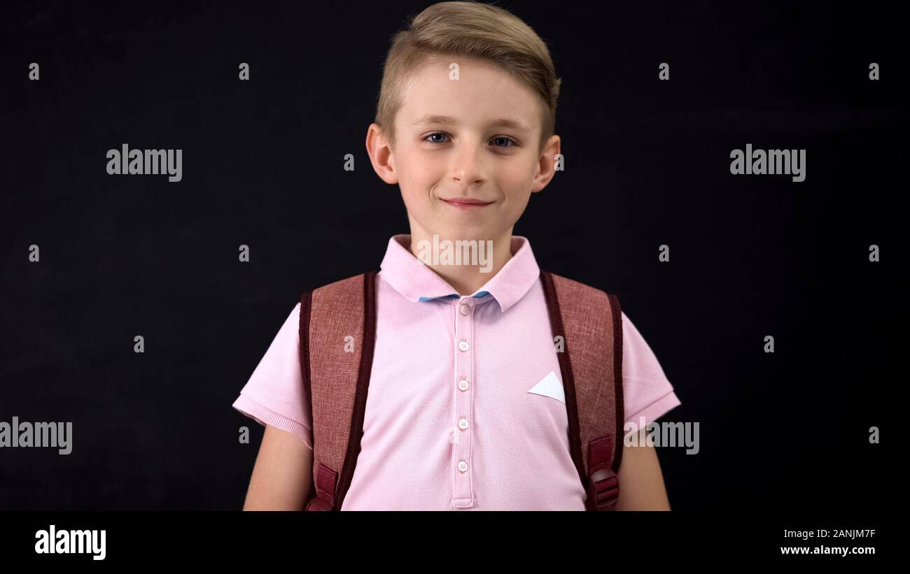 Schoolboy looking at camera against blackboard background, back to ...