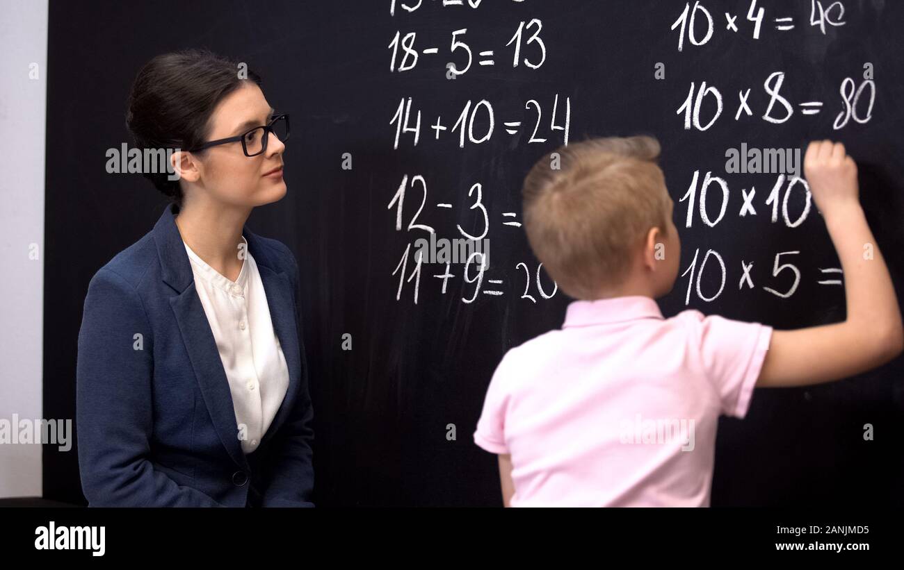 Smiling teacher proud of little boy solving math examples, private ...