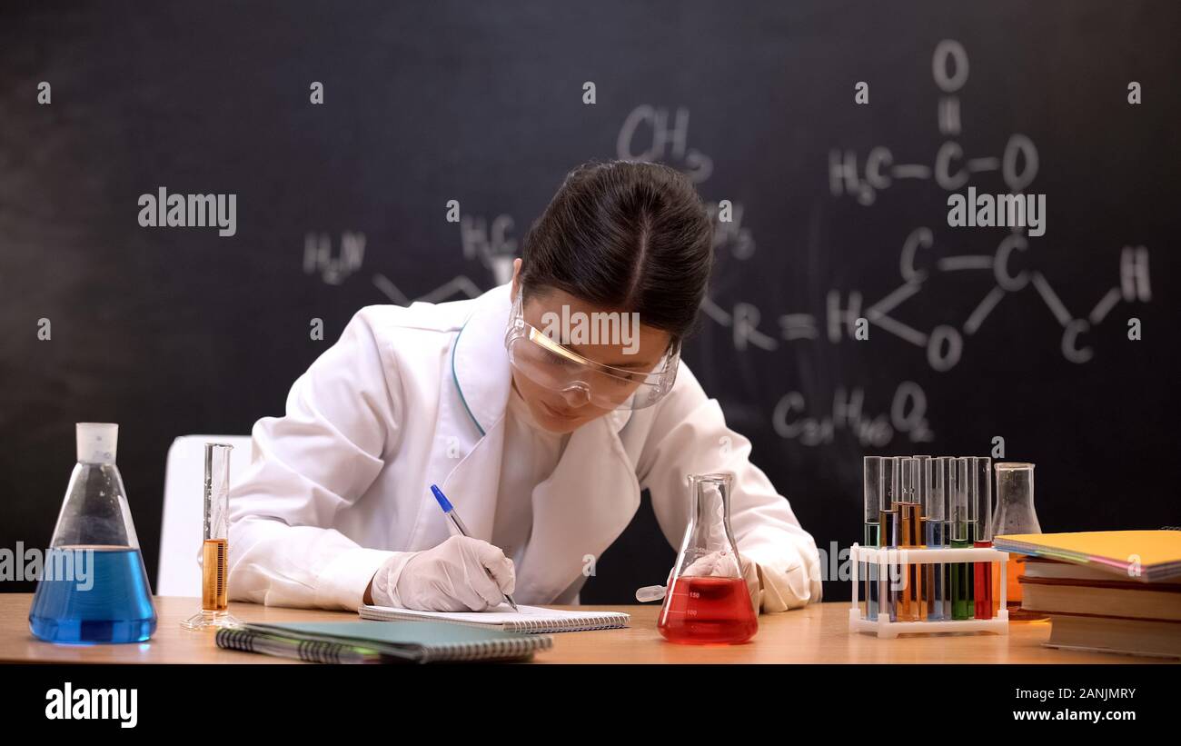 Laboratory worker writing down chemical research results, conducting ...