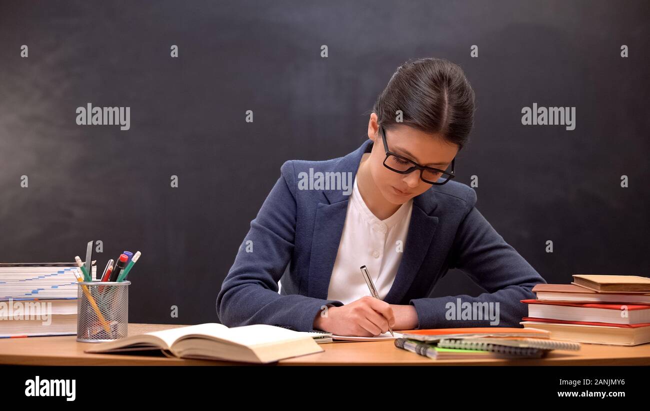 Accurate female teacher checking childrens homework sitting in school ...