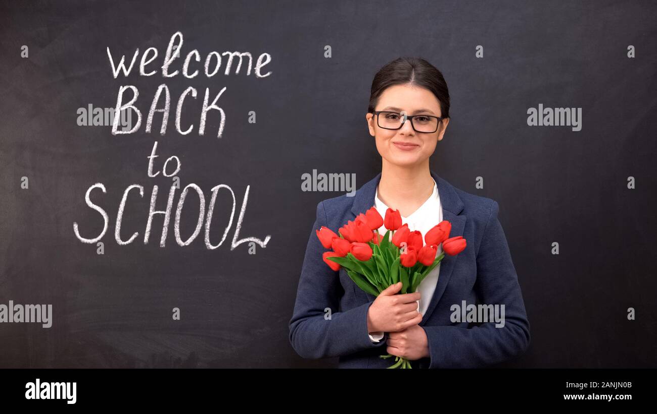 Lady teacher smiling and holding bunch of tulips, welcome back to ...