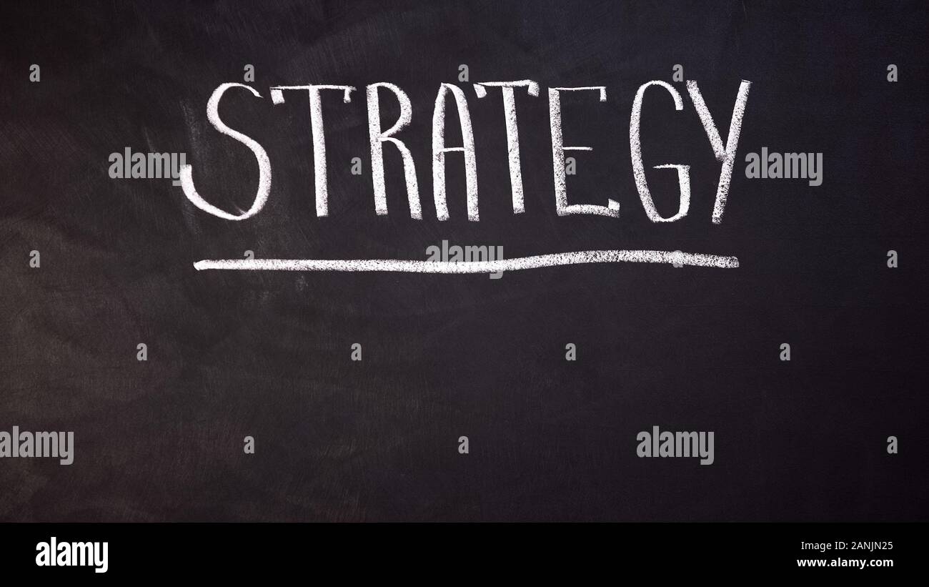 Strategy word written on blackboard, developing business, planning ...