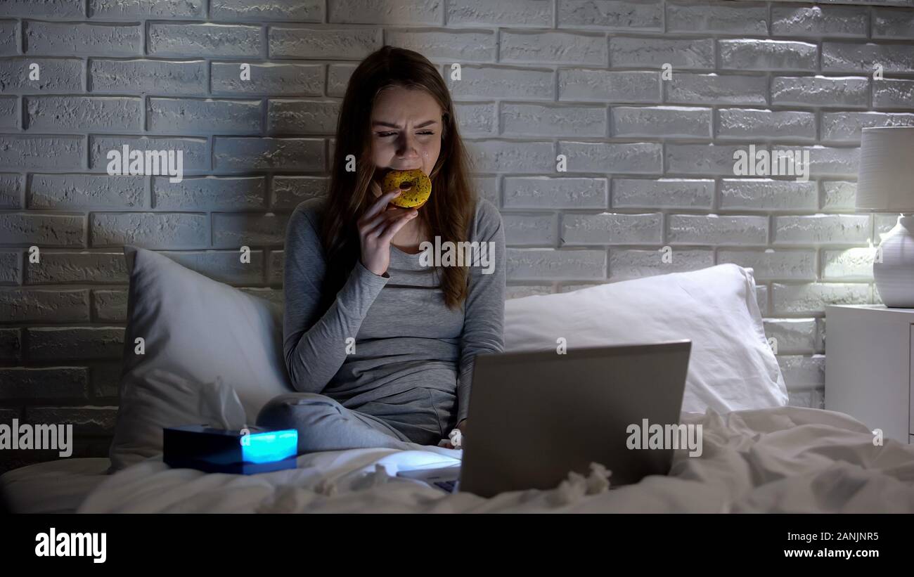 Depressed girl crying and eating donut to overcome stress, watching ...