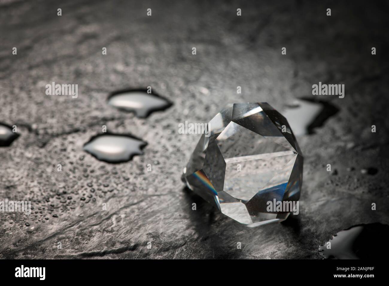 Close-up of a cut and polished crystal on a wet slate slab with water ...