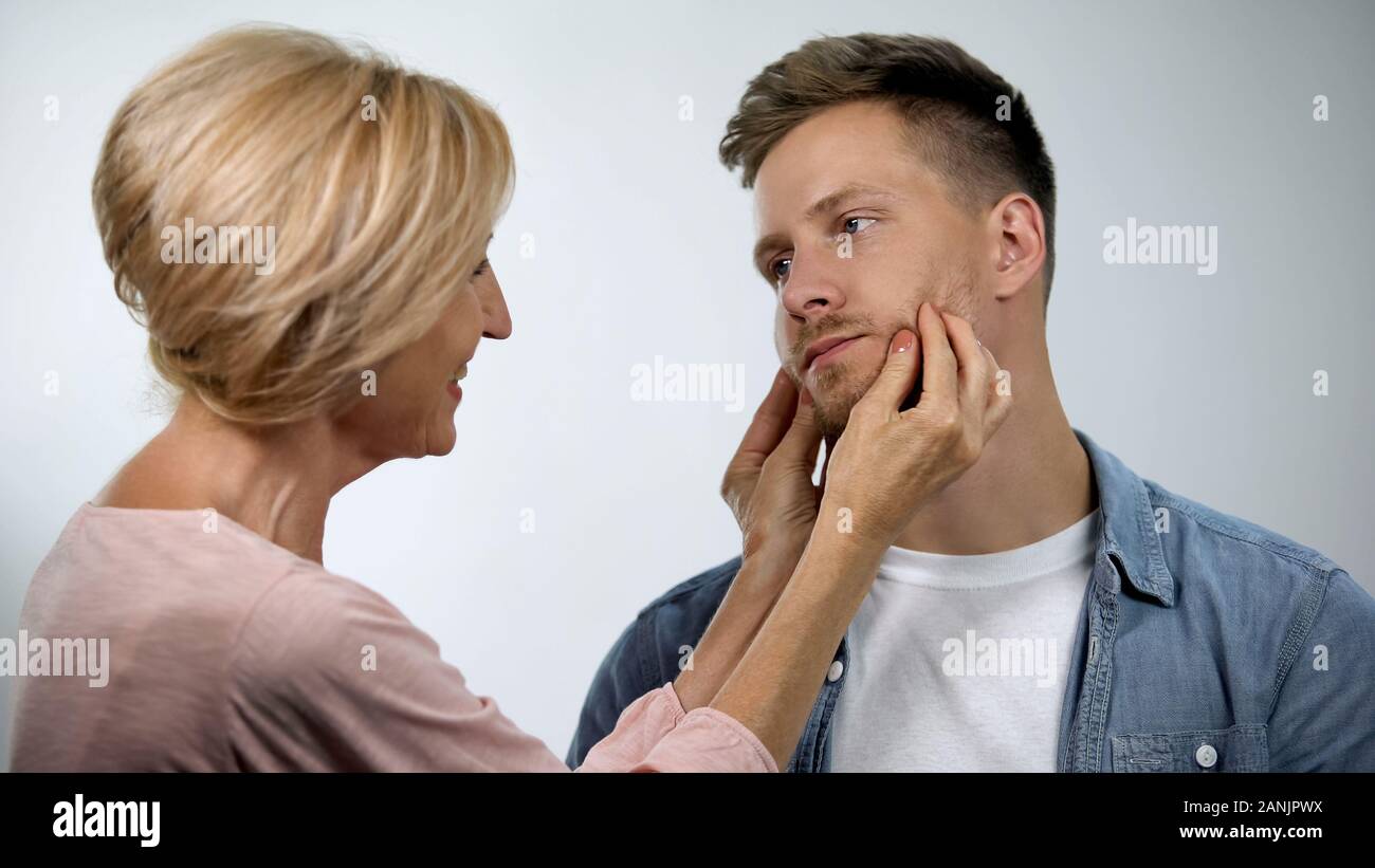 Mother pinching unhappy son cheeks, overprotective parenting style ...