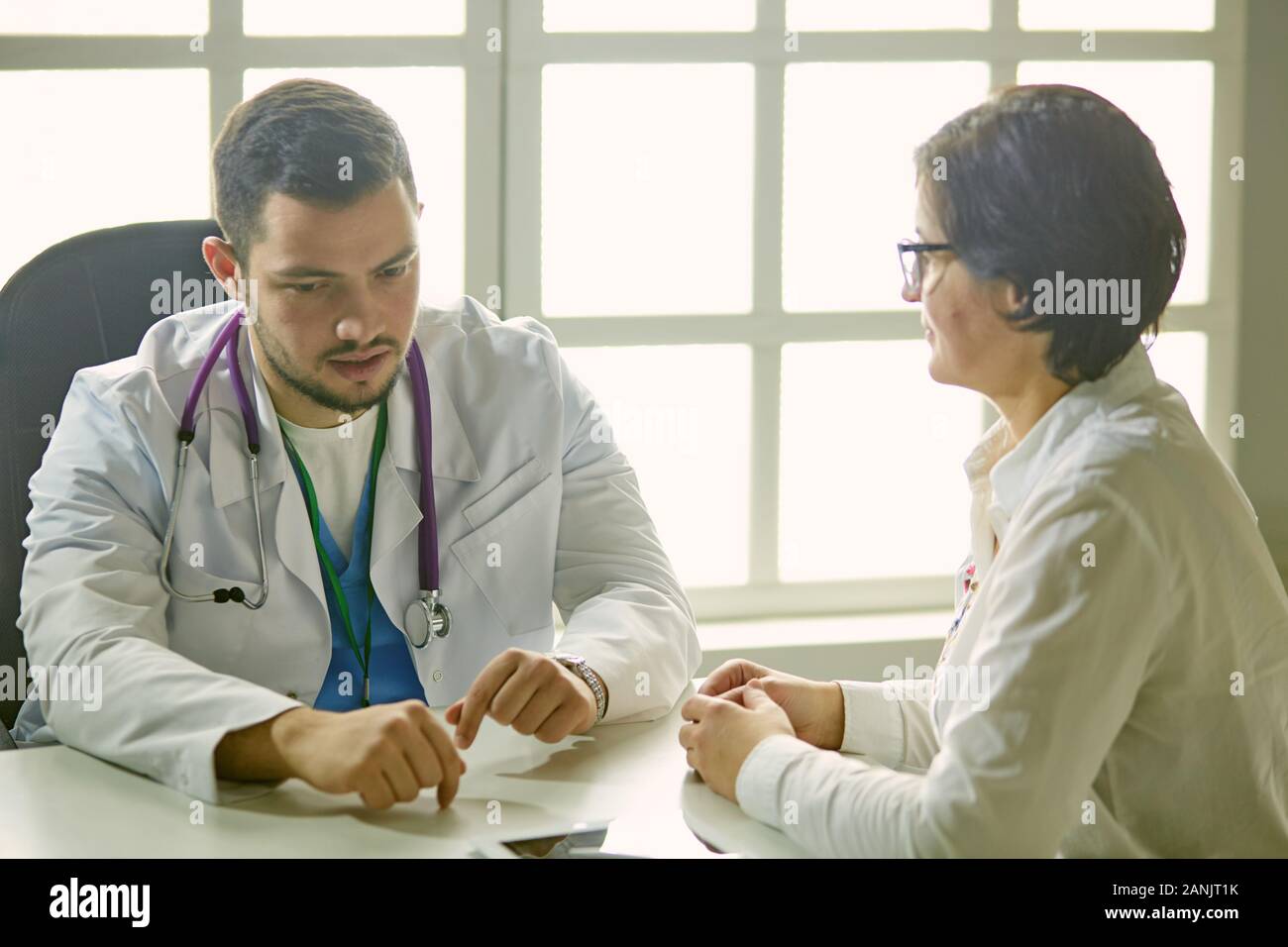 Doctor writing prescription explaining young hi-res stock photography ...