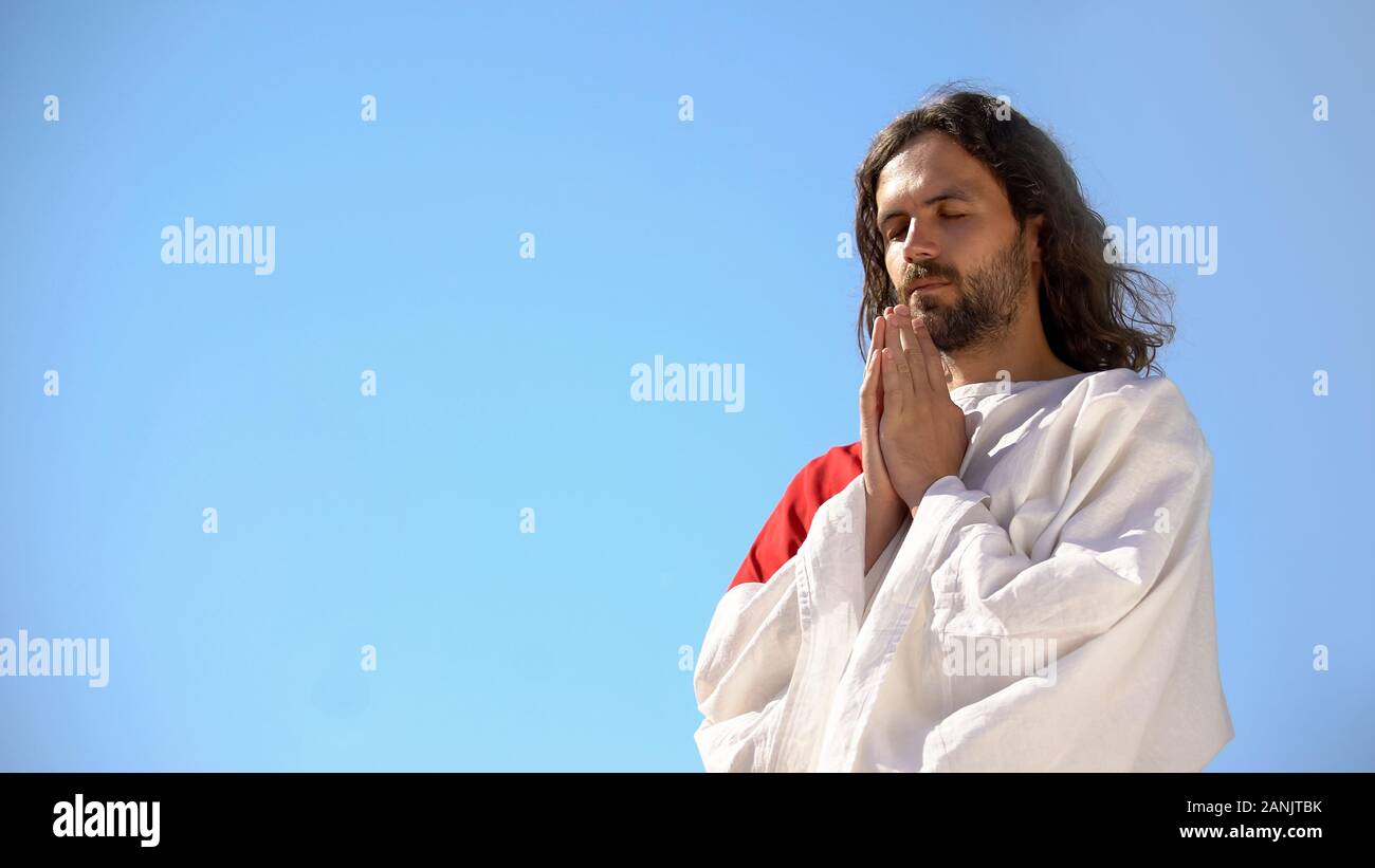 Man in robe praying to God against blue sky background, asking soul ...