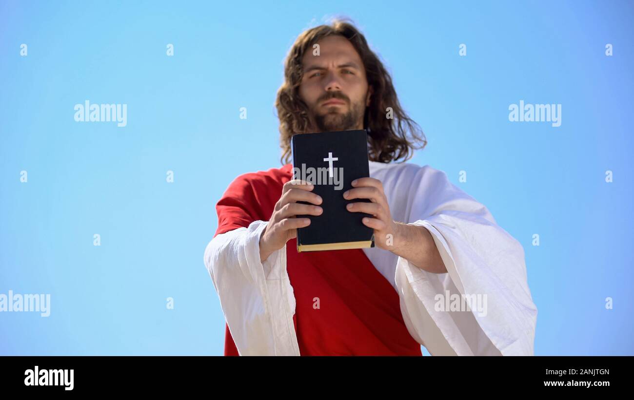 Strict God holding Bible against blue sky, reminding of faith and ...