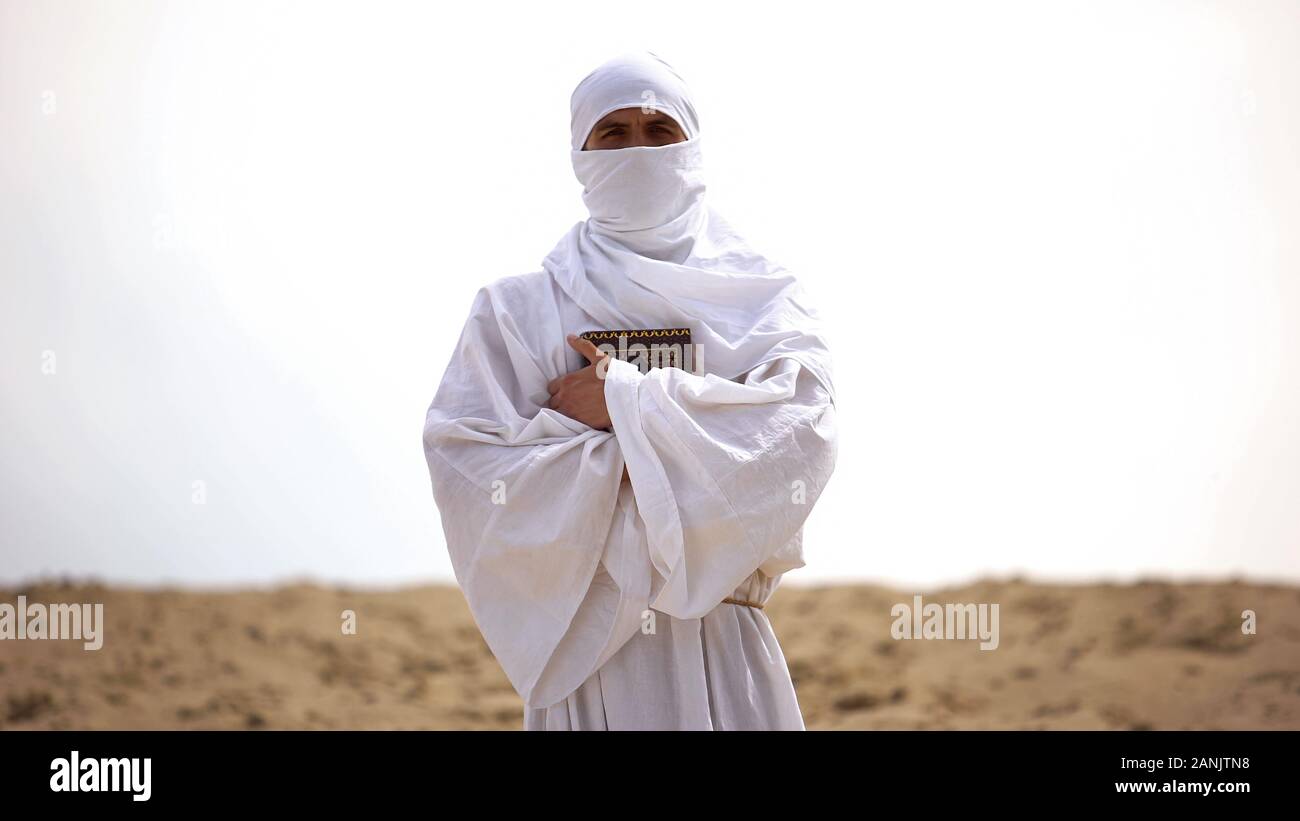 Bedouin in white robe holding Koran, preacher of Islamic faith and ...