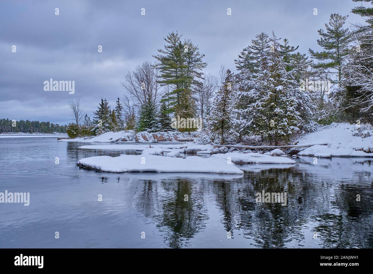 A peaceful winter scene where snow covers the rocks and trees on the ...