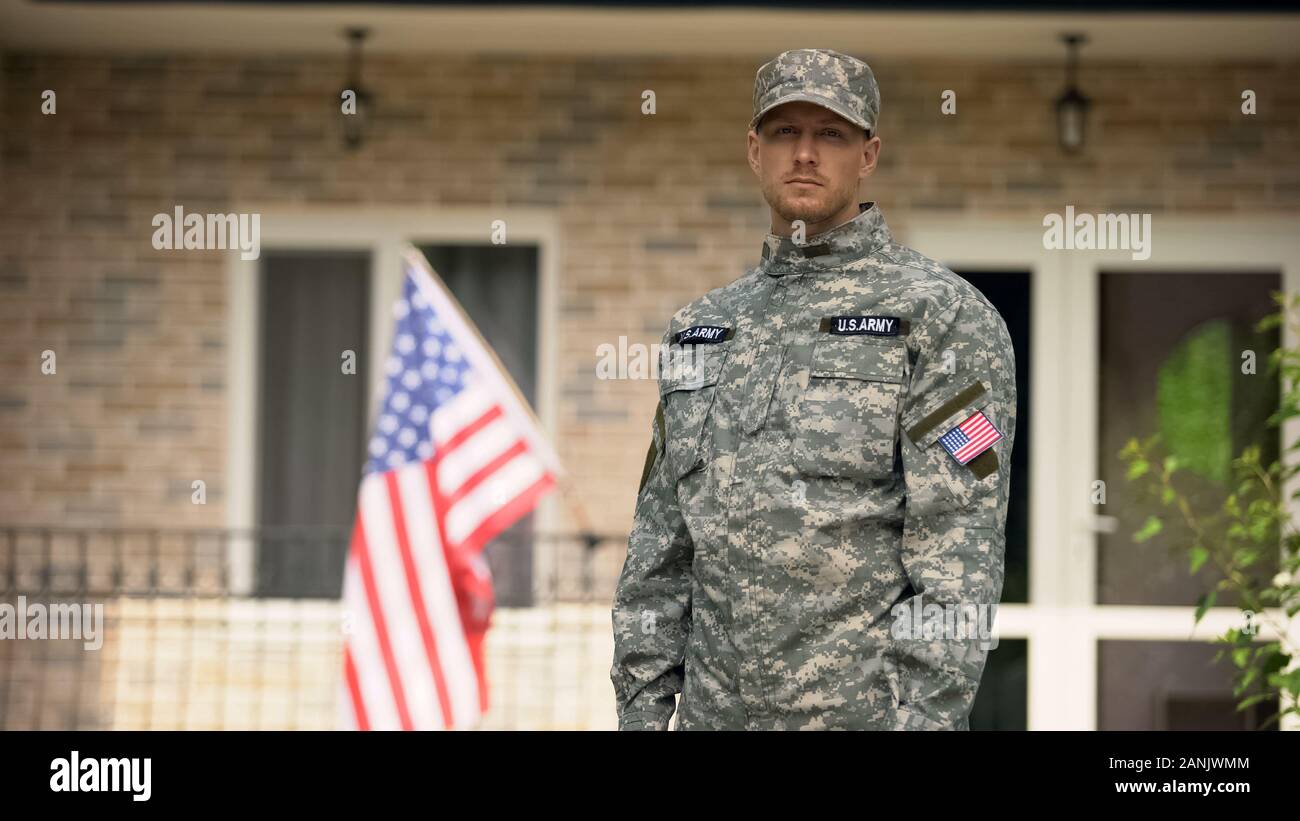 Serious military man standing against house, social insurance for war ...