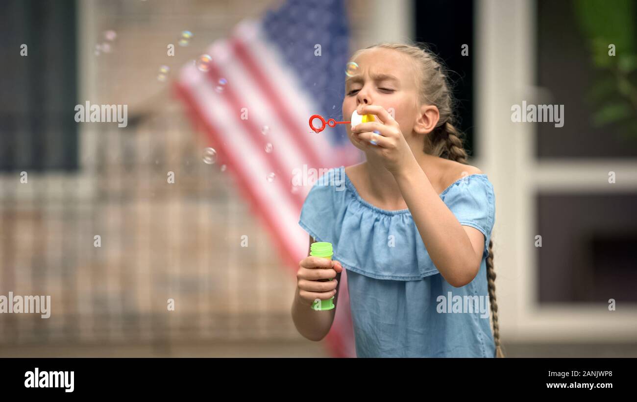 Positive girl blowing soap bubbles, careless and happy childhood ...