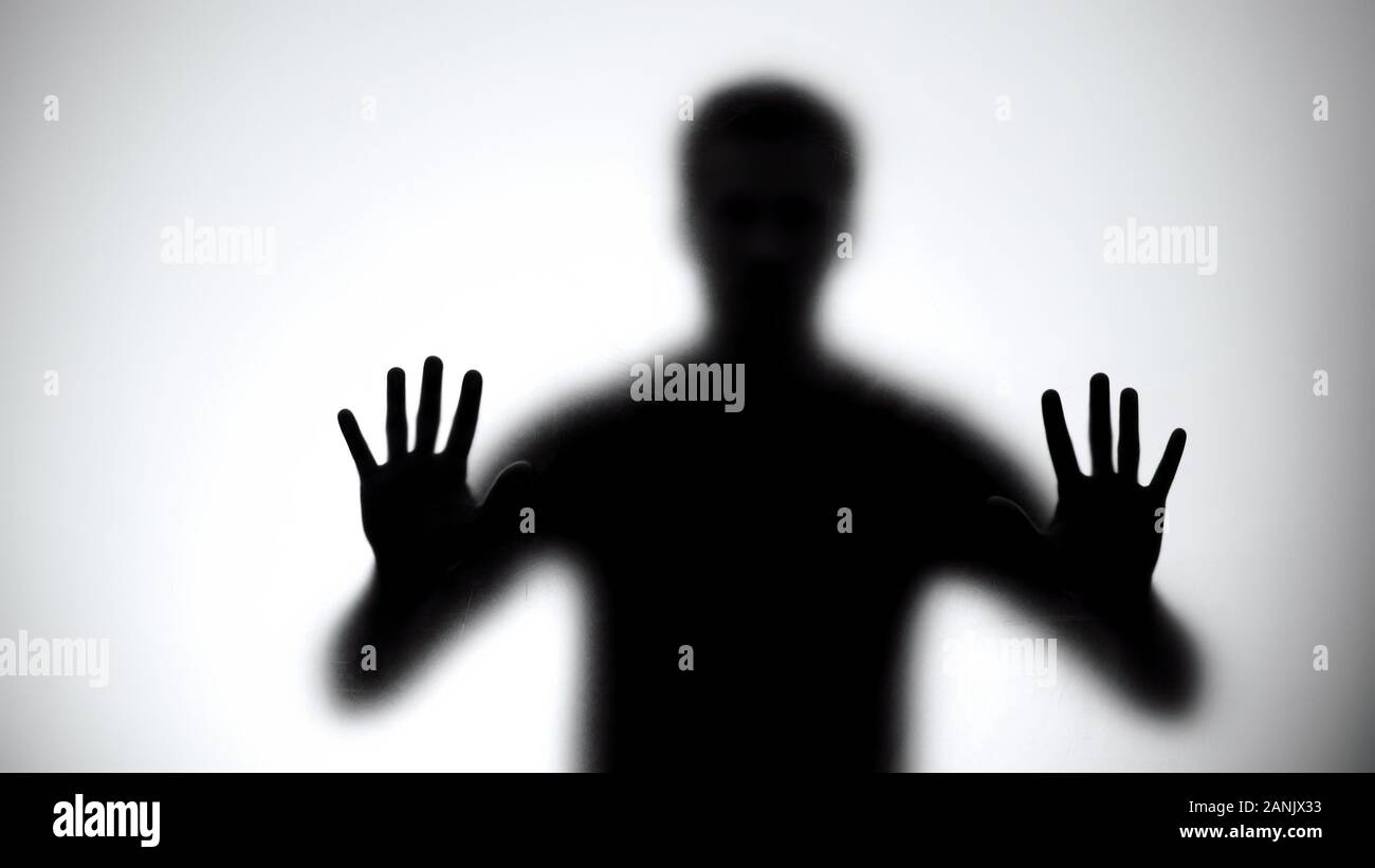 Shadow of trapped man touching glass wall, room escape concept, close ...