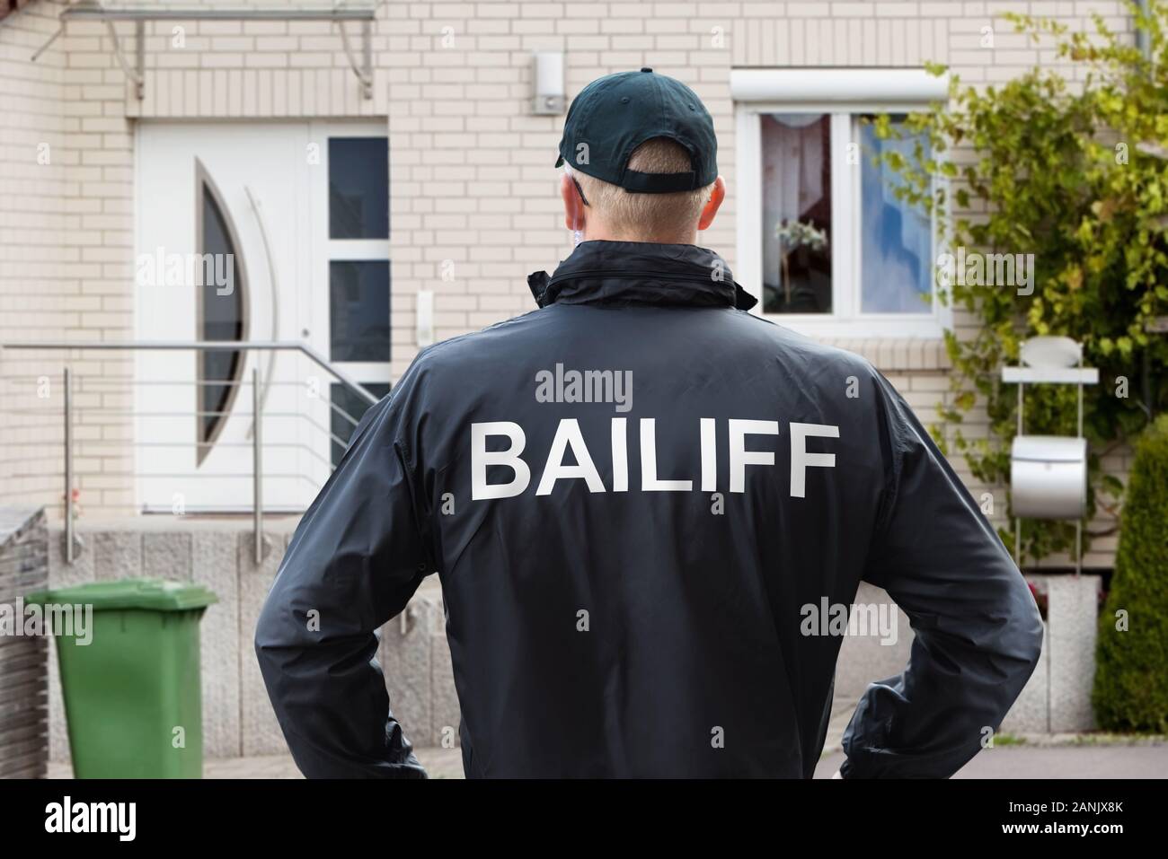 Rear View Of A Male Bailiff Standing With His Hands On Hips At House ...