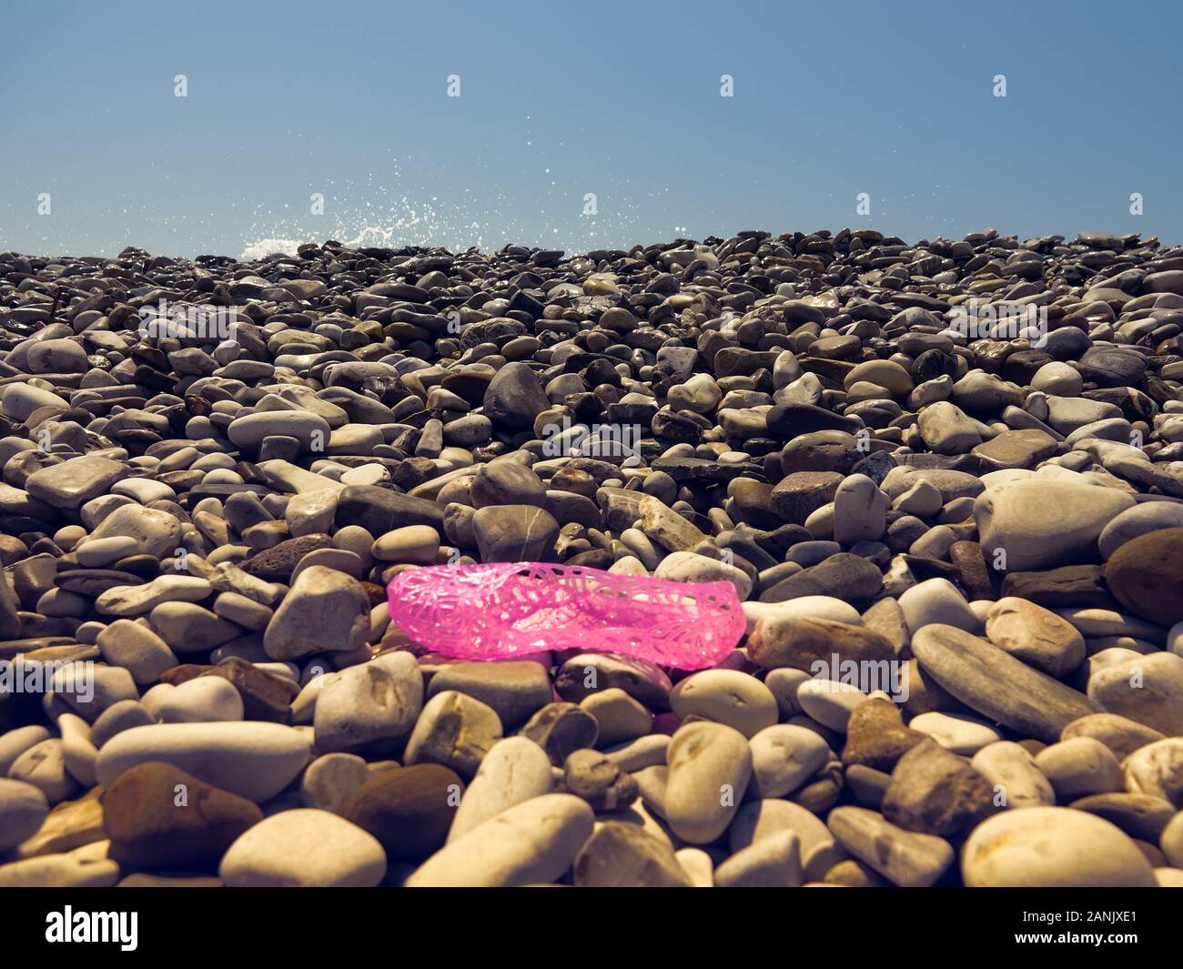 Plastic slipper crumpled and thrown on pebble beach of sea ...
