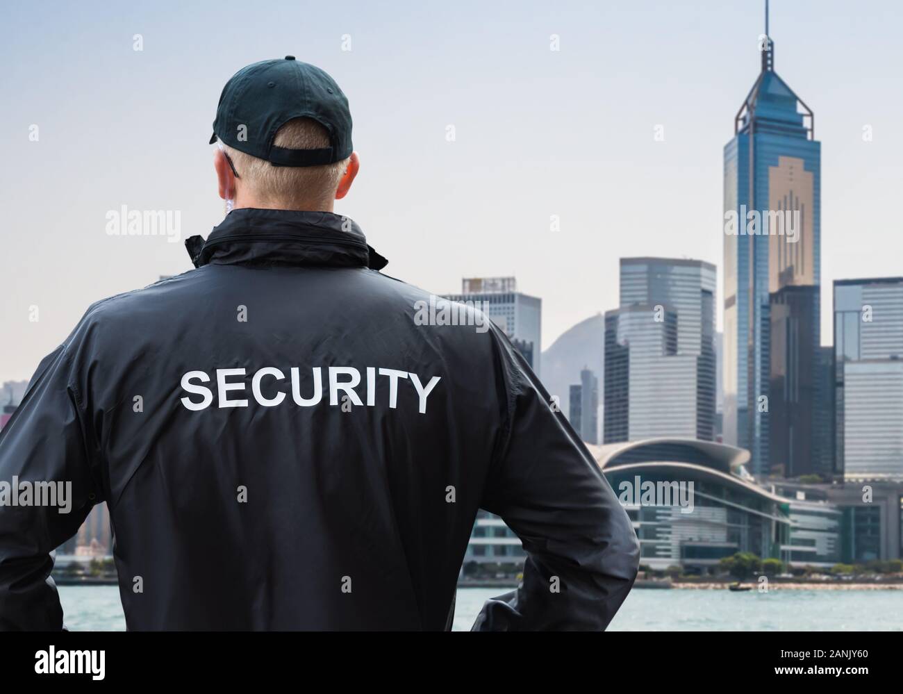 Rear View Of Male Security Guard Looking At City Skyline In Wan Chai ...