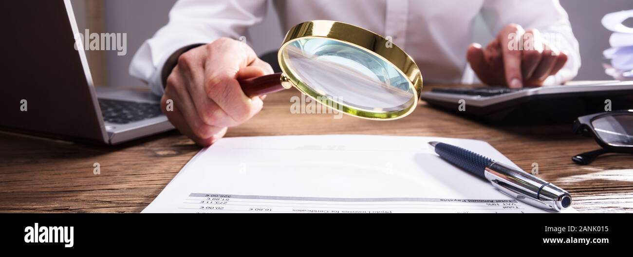Auditor Analyzing Bill Through Magnifying Glass On Desk Stock Photo - Alamy