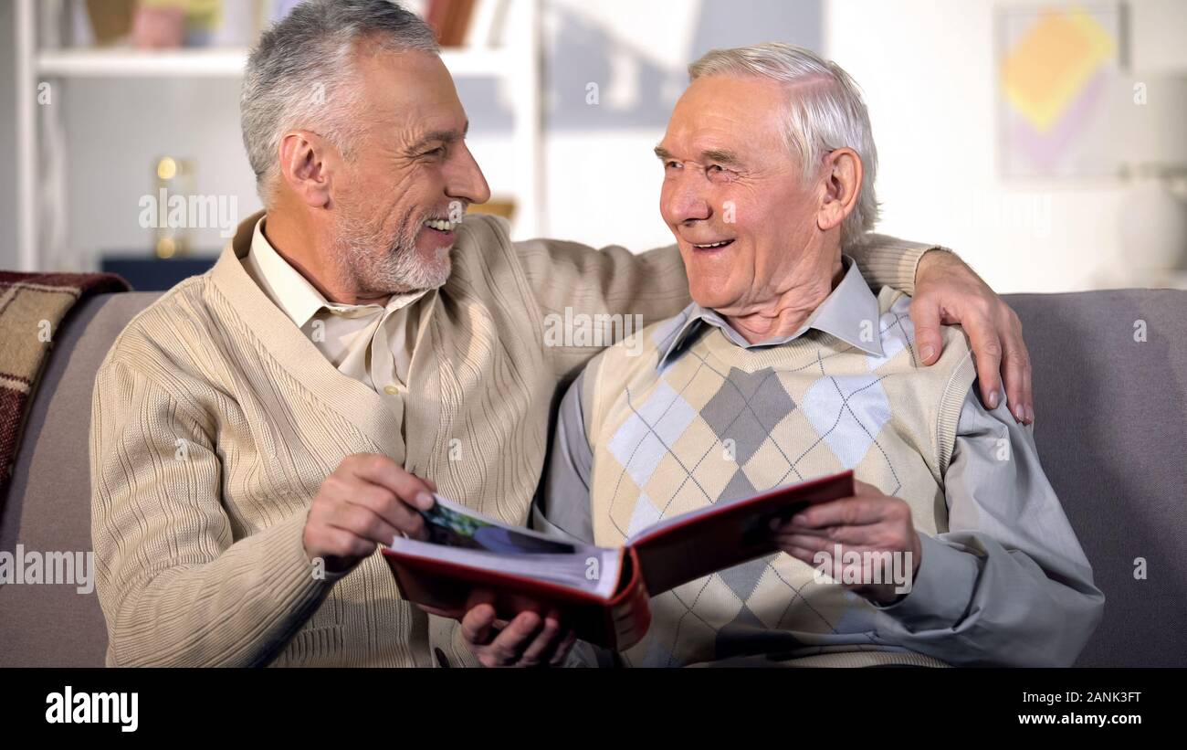 Aged male friends having fun watching album photos together, friendship ...
