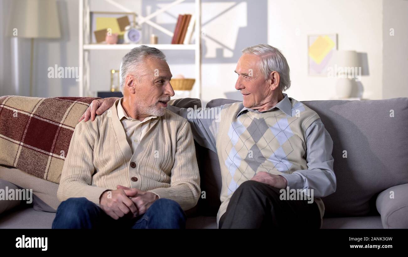 Two old friends talking having fun sitting on sofa, positive mood ...