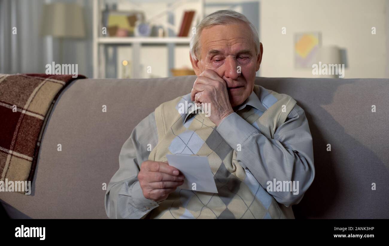 Crying elderly man looking at photo, remembering old lost friend ...