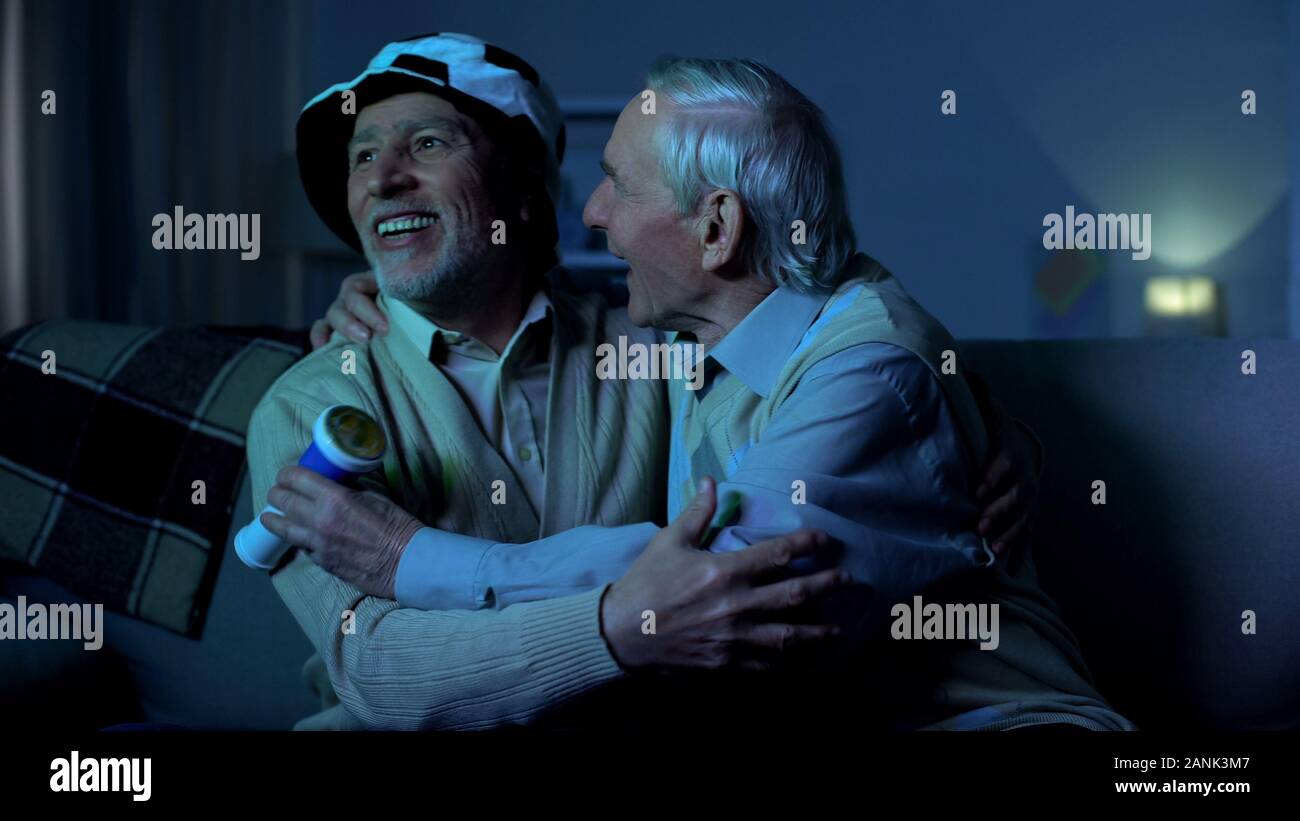 Happy senior fans hugging cheering for team watching sport game ...