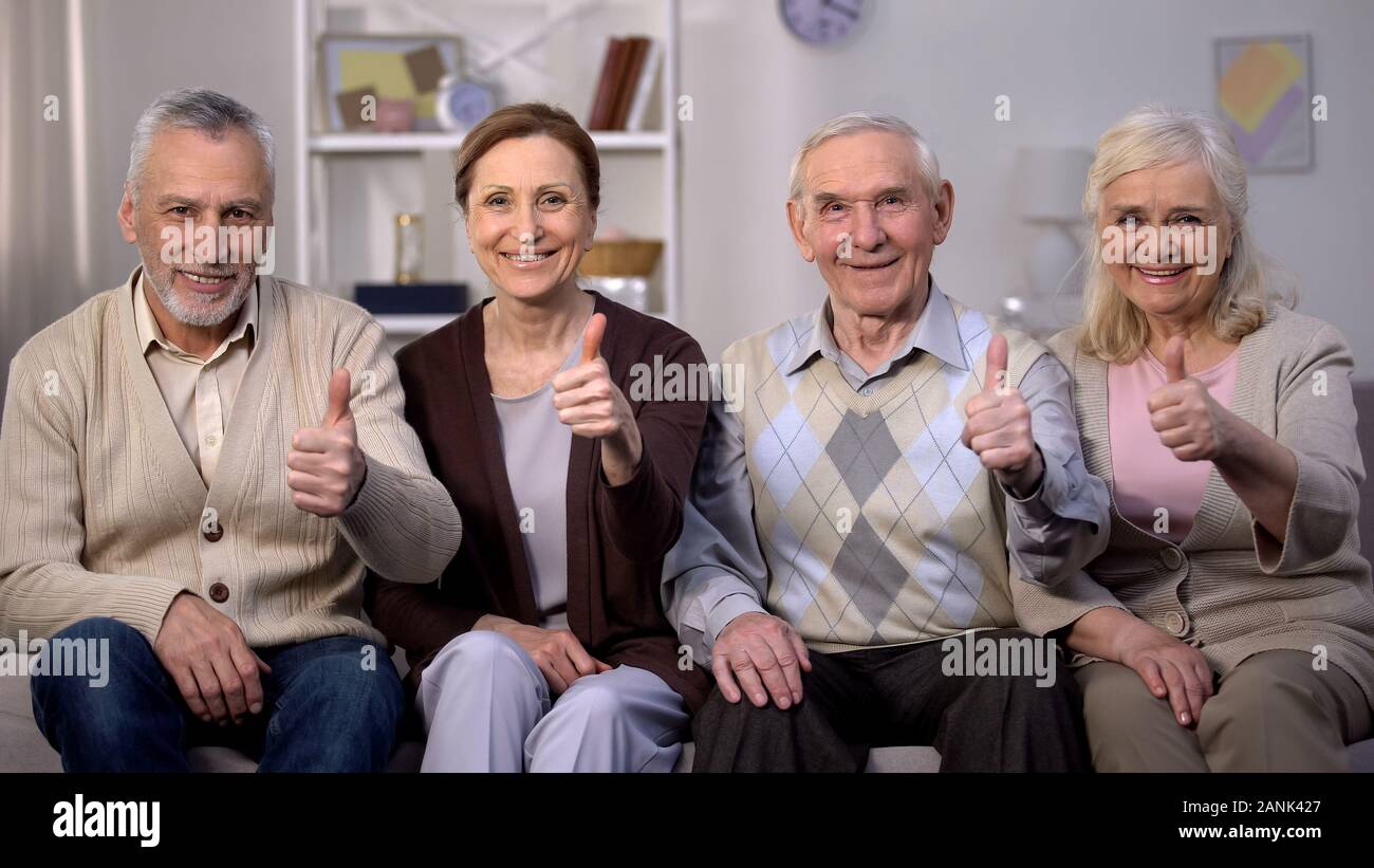 Smiling elderly people showing thumbs up on camera, social reform ...