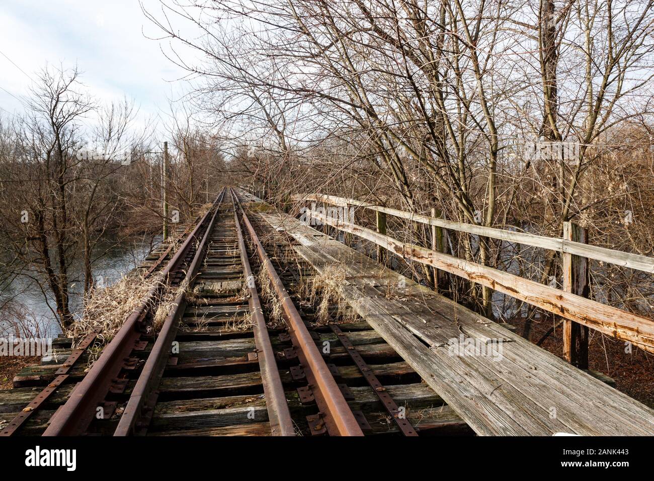 Old abandoned railroad bridge stretches over a river and into the far, wooded distance, seen ...