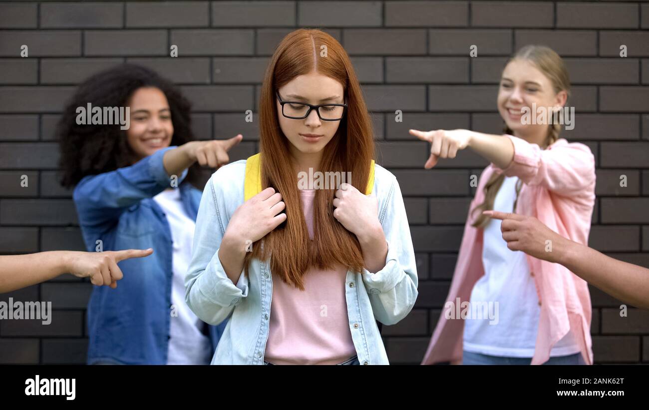 Teenagers pointing fingers teasing new smart classmate in eyeglasses ...