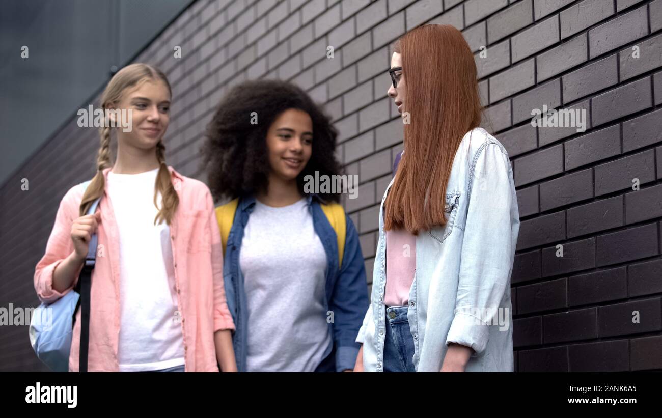 Two school pupils bullying modest red-haired teenager, pushing scared ...