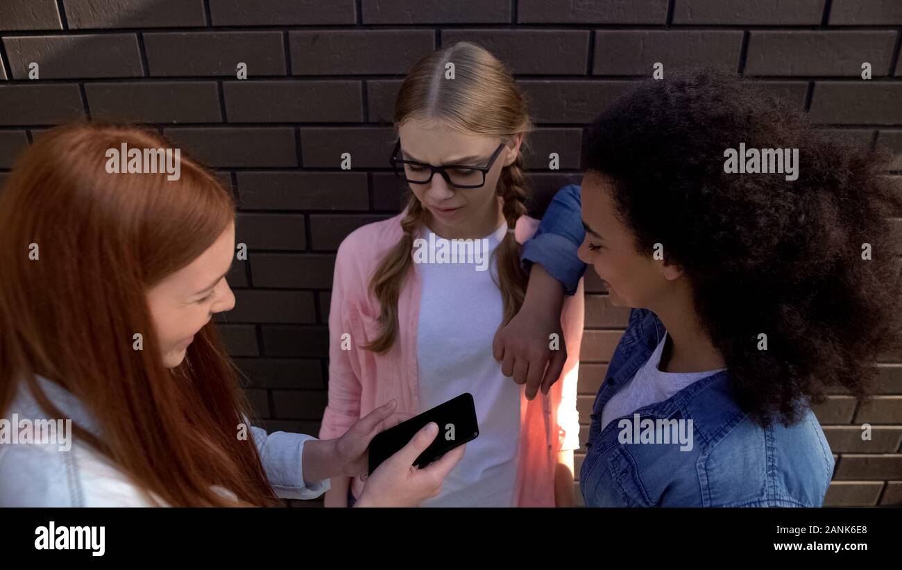 Mocking students checking schoolmate smartphone and laughing, teenage ...
