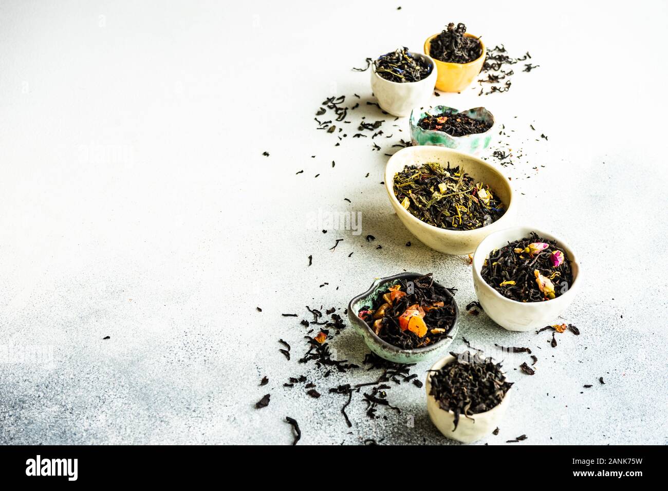 Different tea varieties in ceramic bowls on stone rustic background ...