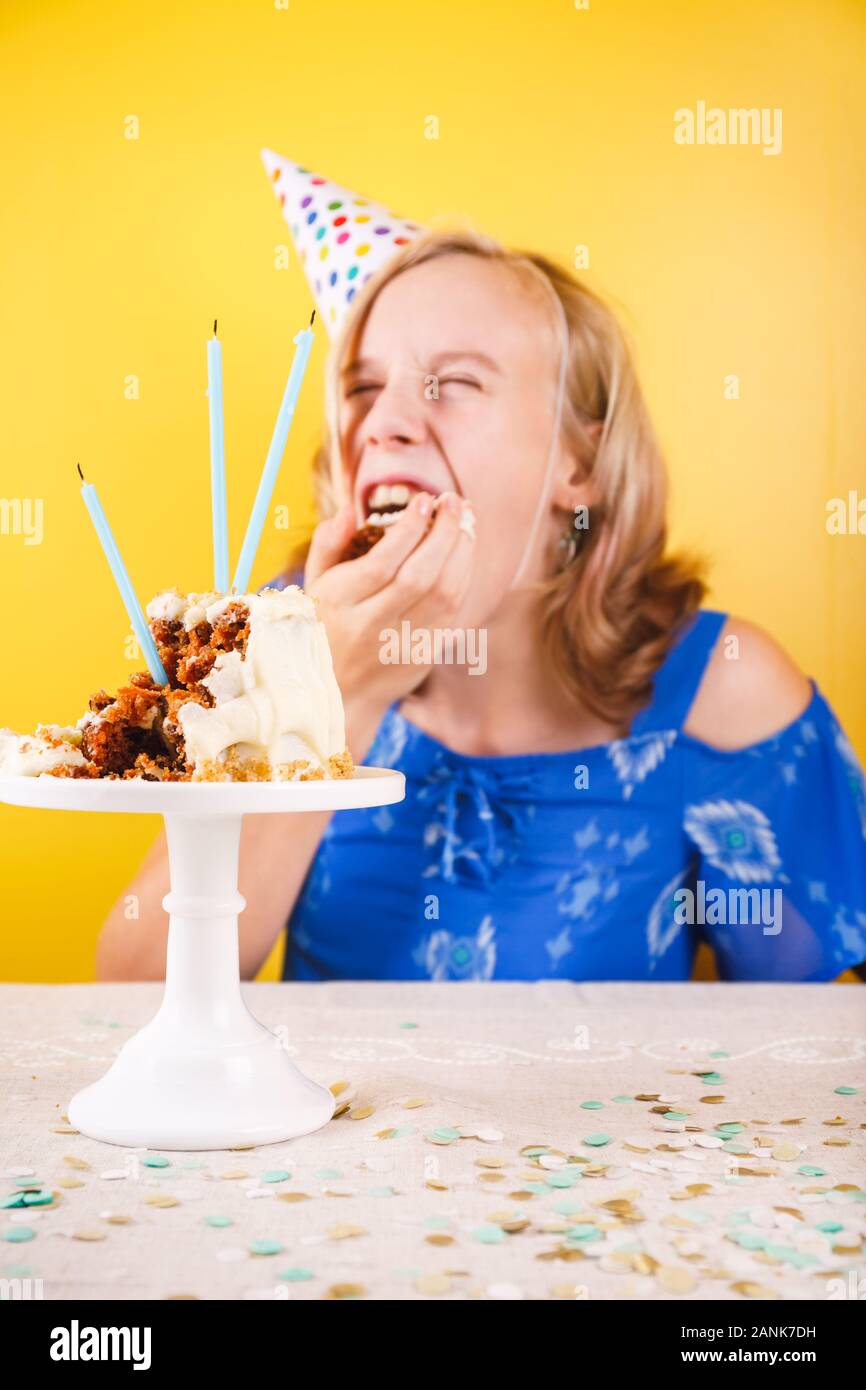 Teenage girl eating birthday cake with her hands. One person party ...