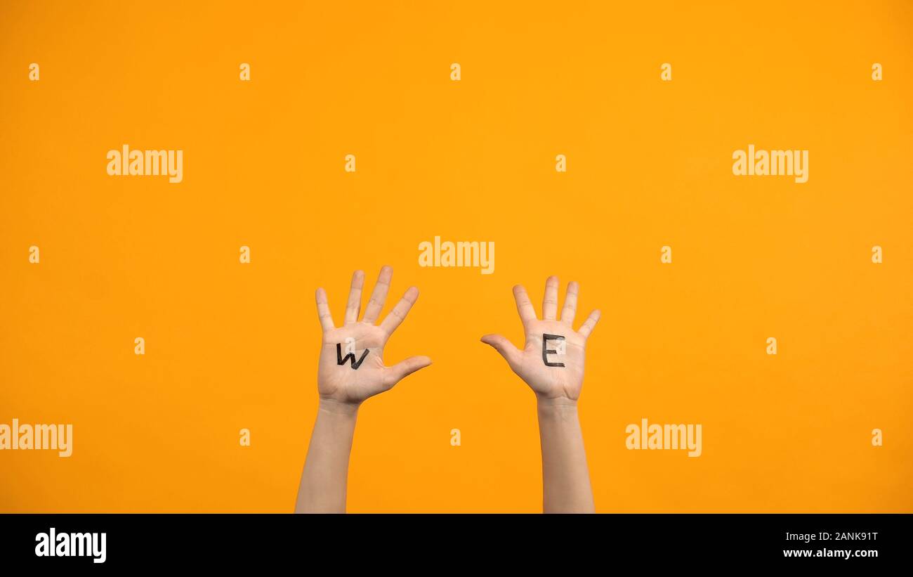We written palms on orange background, volunteers raising hands ...