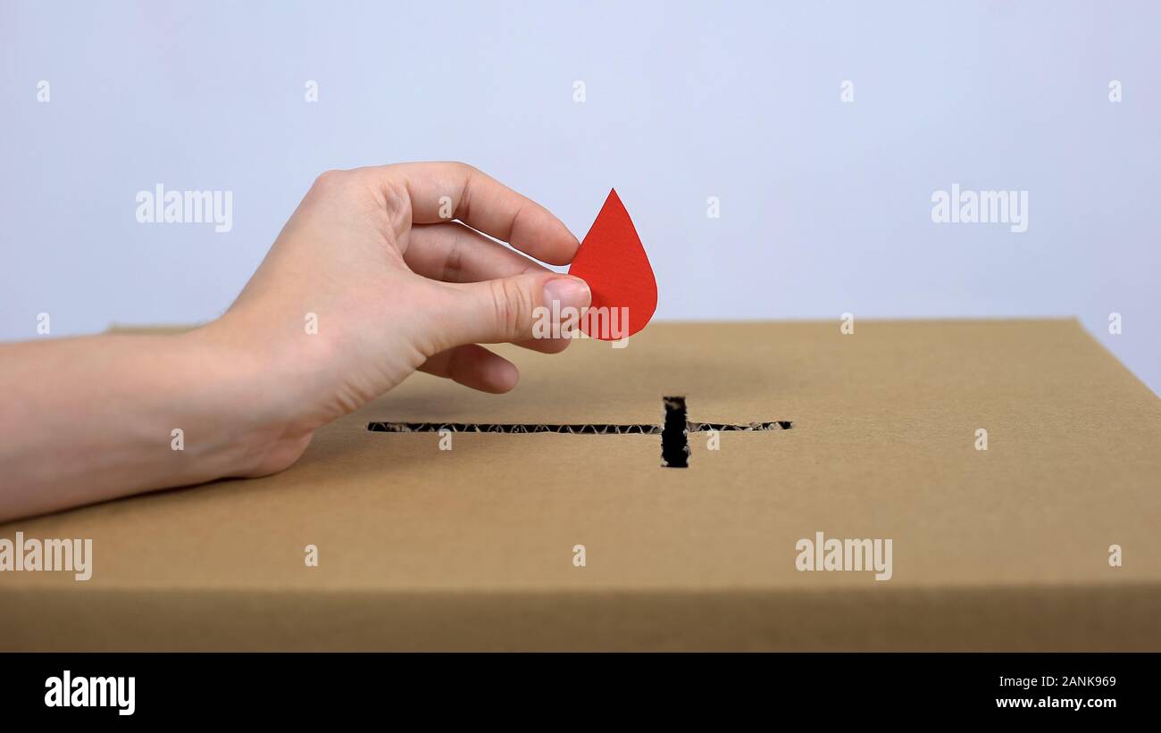 Female hand putting red drop sign in church box, blood donation, donor ...