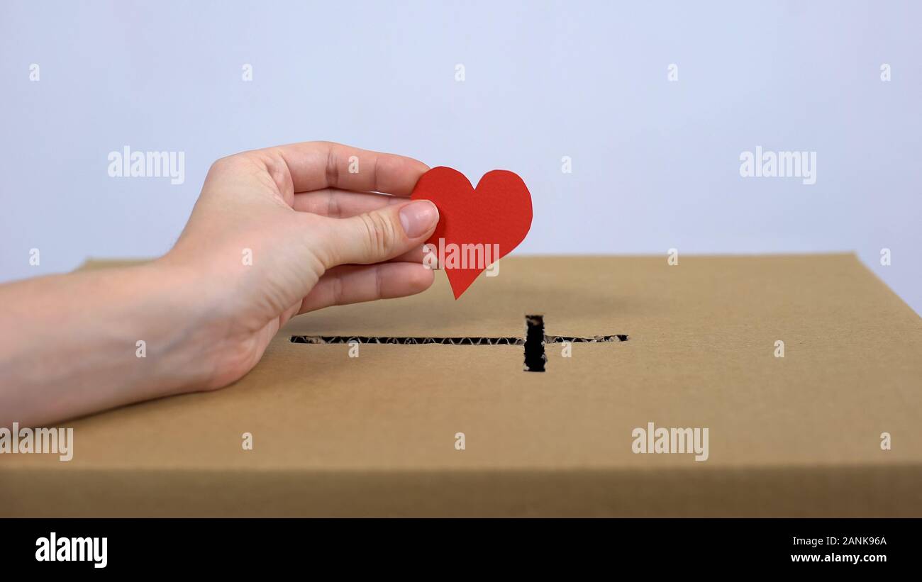 Female hand putting red heart sign church donation box, religious mercy ...
