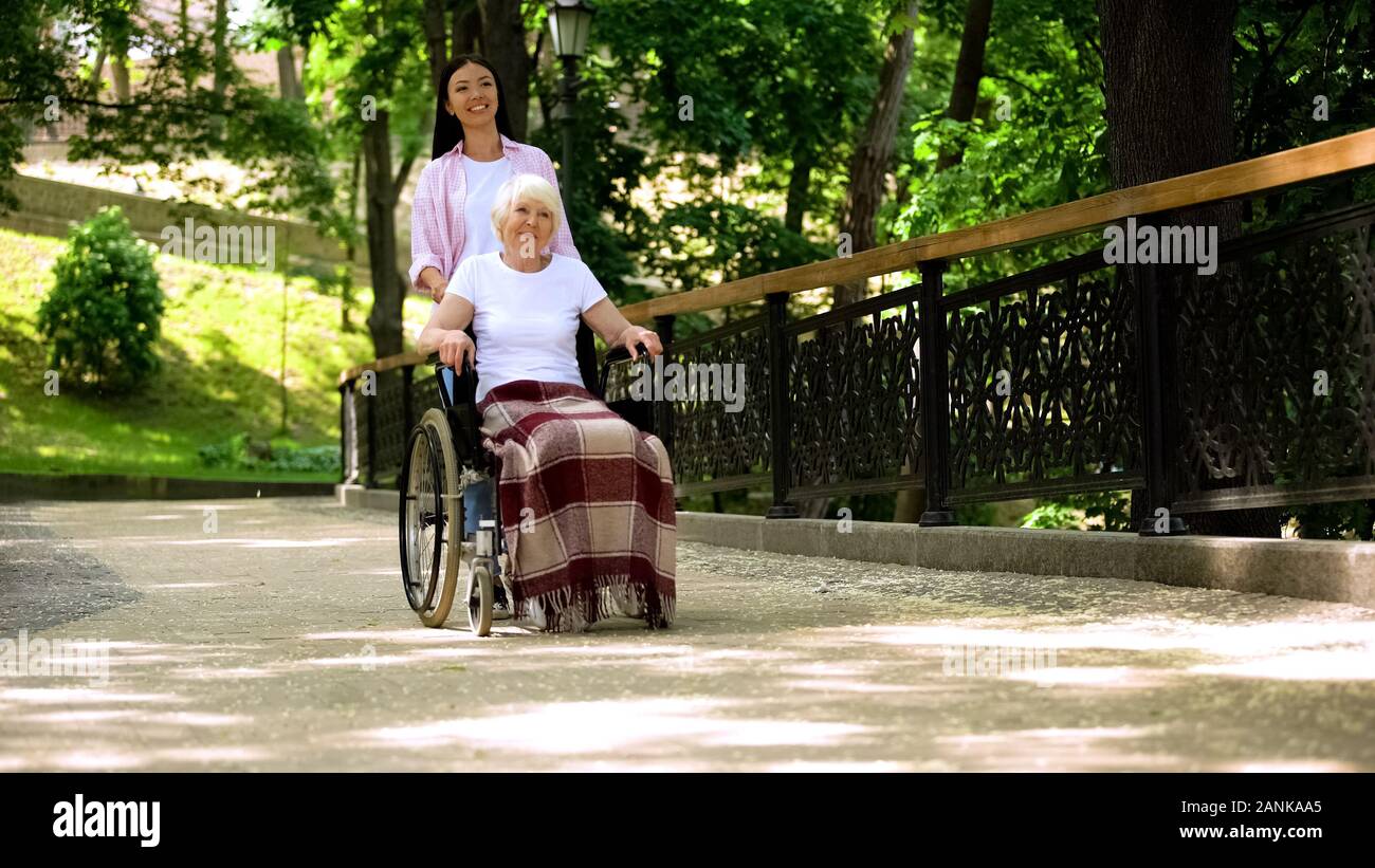 Granddaughter pushing old woman in wheelchair hospital garden, support ...