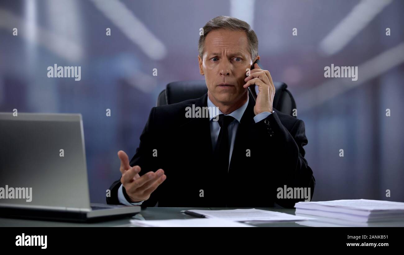 Stressed company male boss talking phone with employee at workplace ...