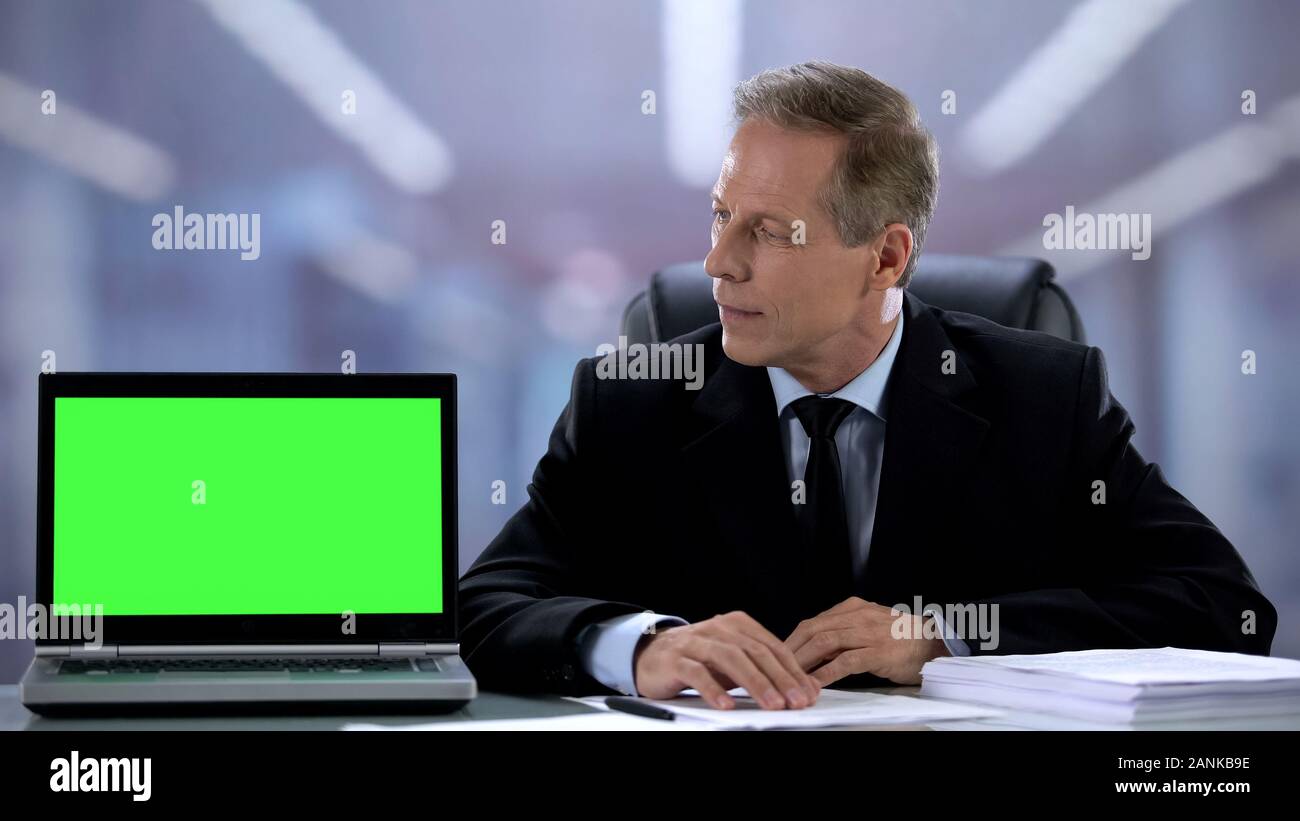 Office manager looking at laptop with green screen, financial app ...