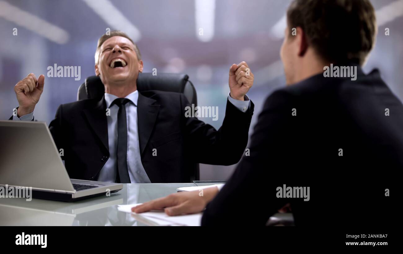 Employee and employer laughing out loud, telling jokes at work in ...