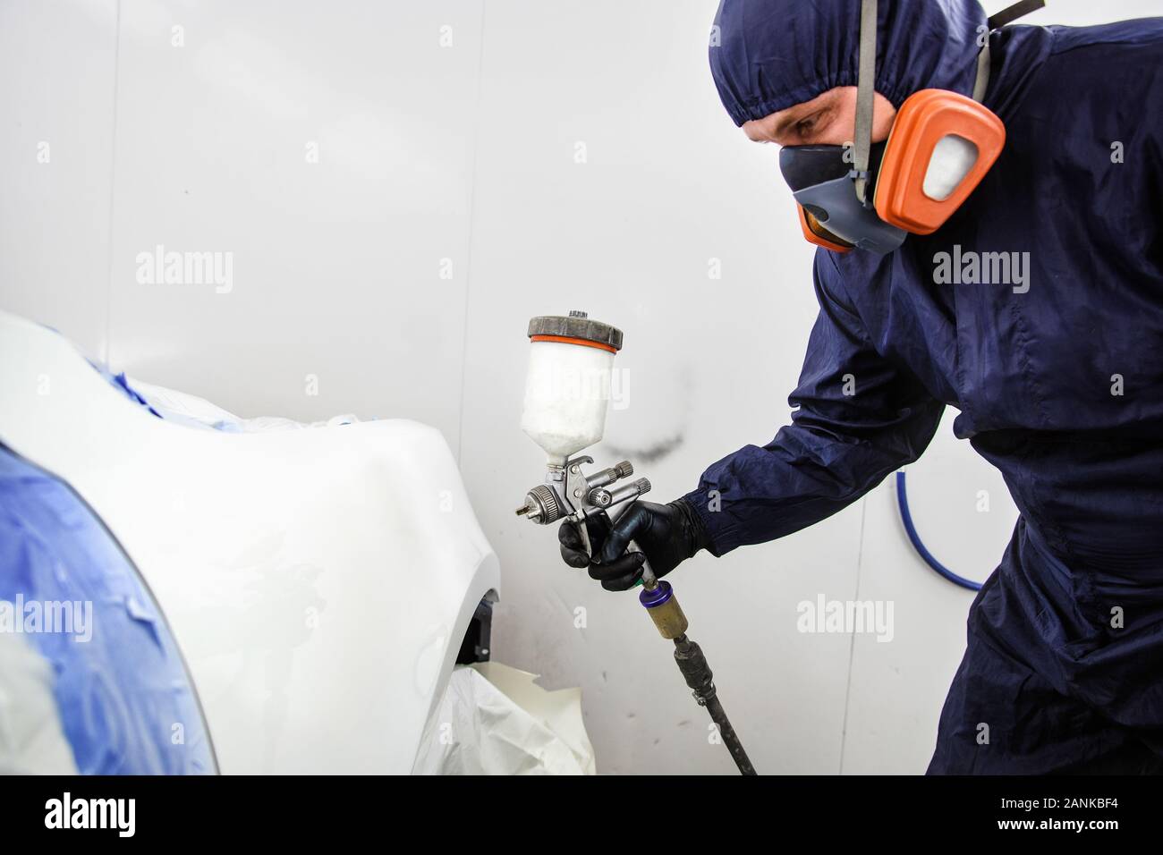 worker in overalls with a respirator and spray gun in his hand in the ...