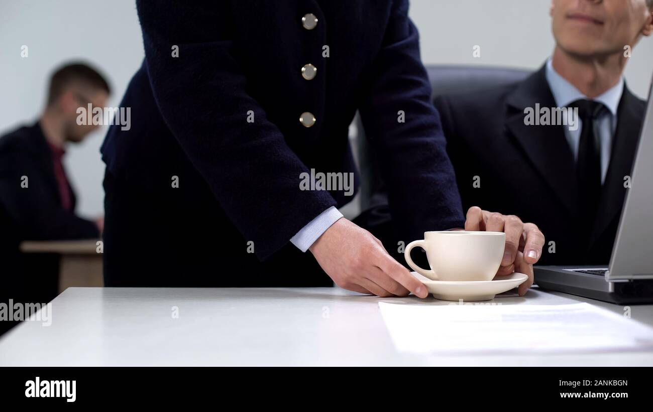 Male manager touching hand of secretary bringing coffee, secret ...