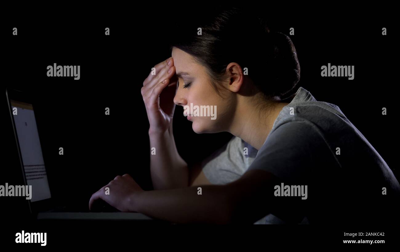 Female student typing report on laptop late at night, tired with ...