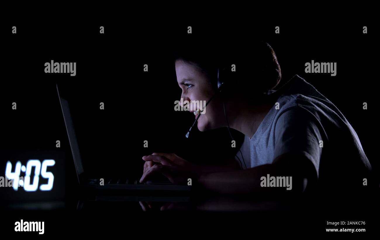 Female gamer in headset playing video games late at night, computer ...