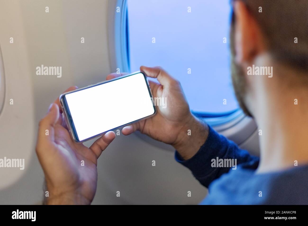 Mockup smartphone airplane. Young attractive european man holding blank ...