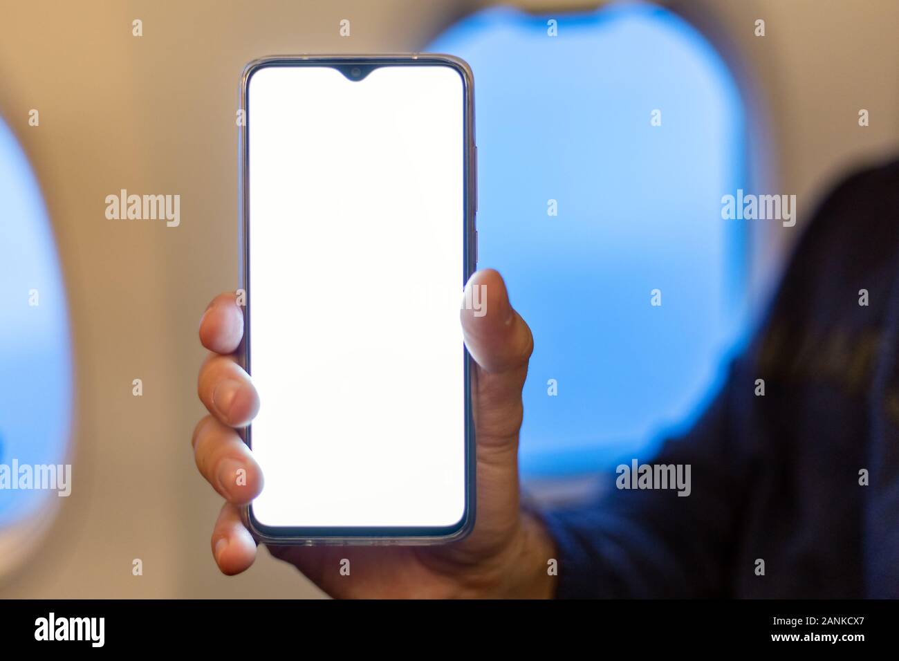 Mockup smartphone airplane. Young attractive european man holding blank ...