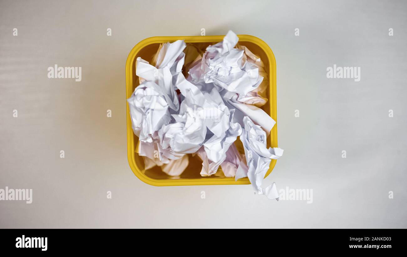 Overflowing waste paper in yellow garbage bin, recycling concept ...