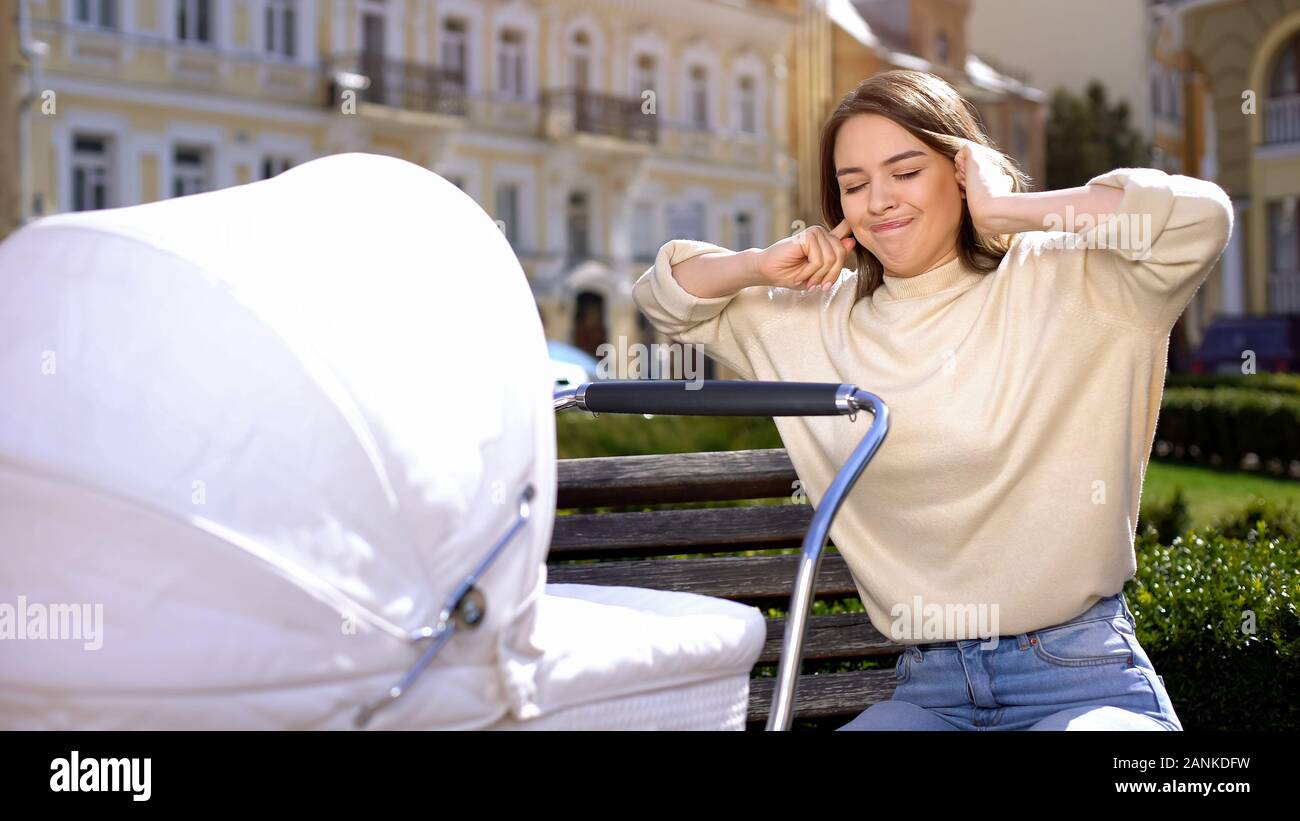 Angry young mom covering ears irritated by crying baby, motherhood ...